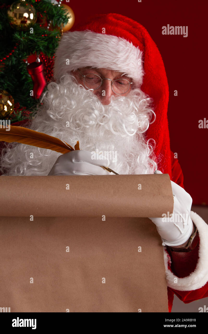 Santa Claus sitting at home and writing on old paper roll to do list ...