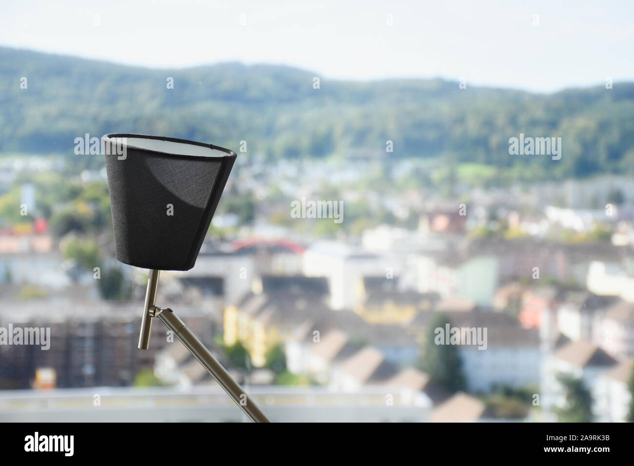 A modern flexible table lamp pointing upwards in front of a window with ...