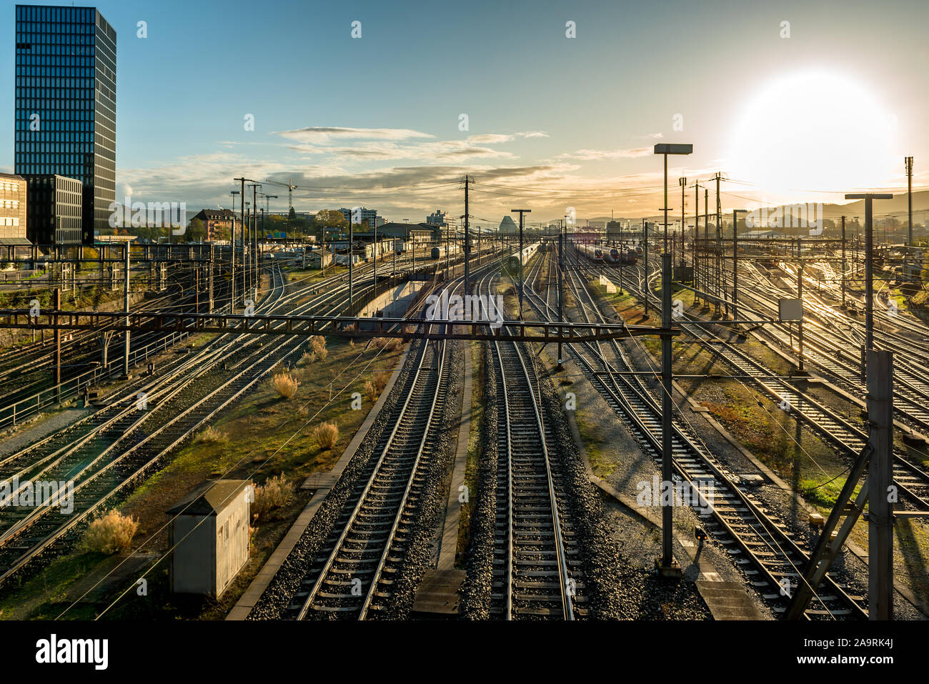 Modern European railway station at sunrise with rail tracks and trains ...