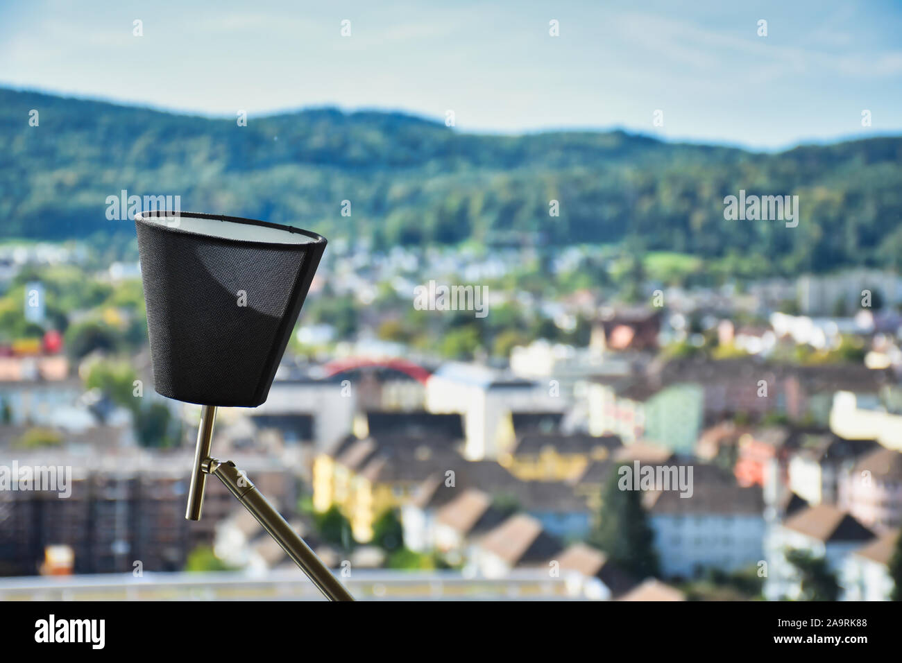 A modern flexible table lamp pointing upwards in front of a window with ...