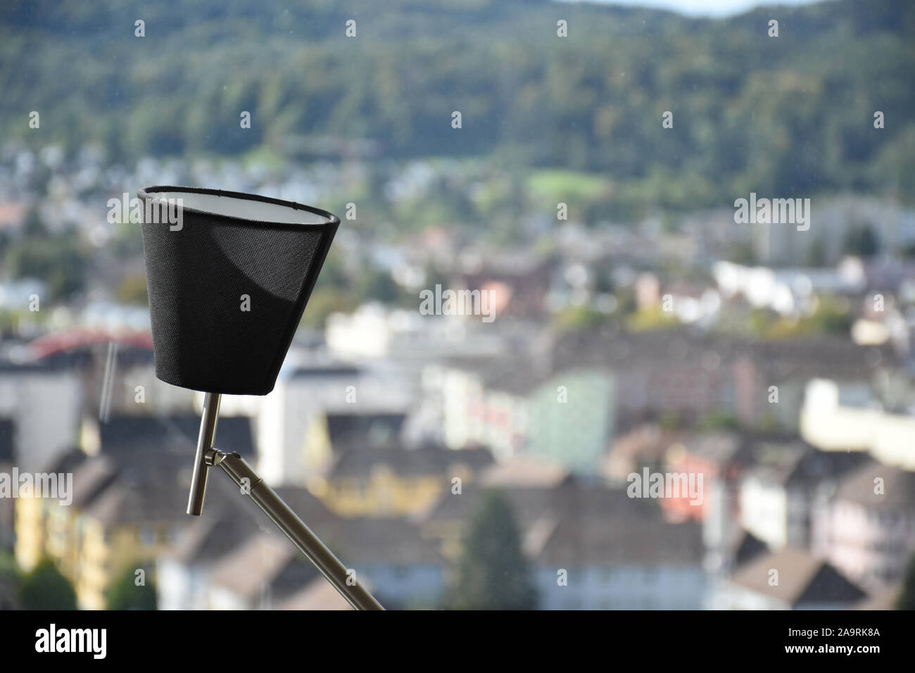A modern flexible table lamp pointing upwards in front of a window with ...