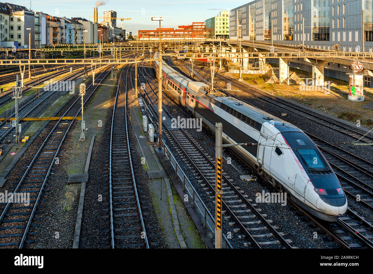 Modern European railway station at sunrise with rail tracks and trains ...
