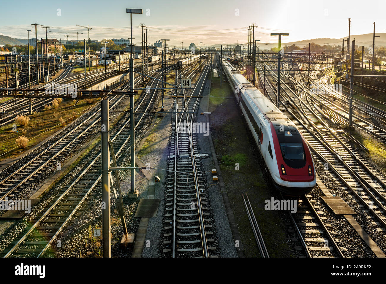 Modern European railway station at sunrise with rail tracks and trains ...