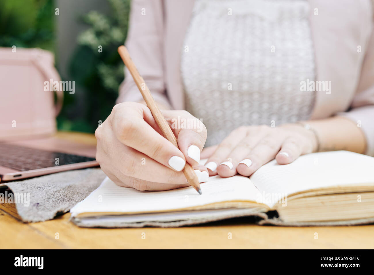 Manicured hands of female student taking notes in planner and writing ...