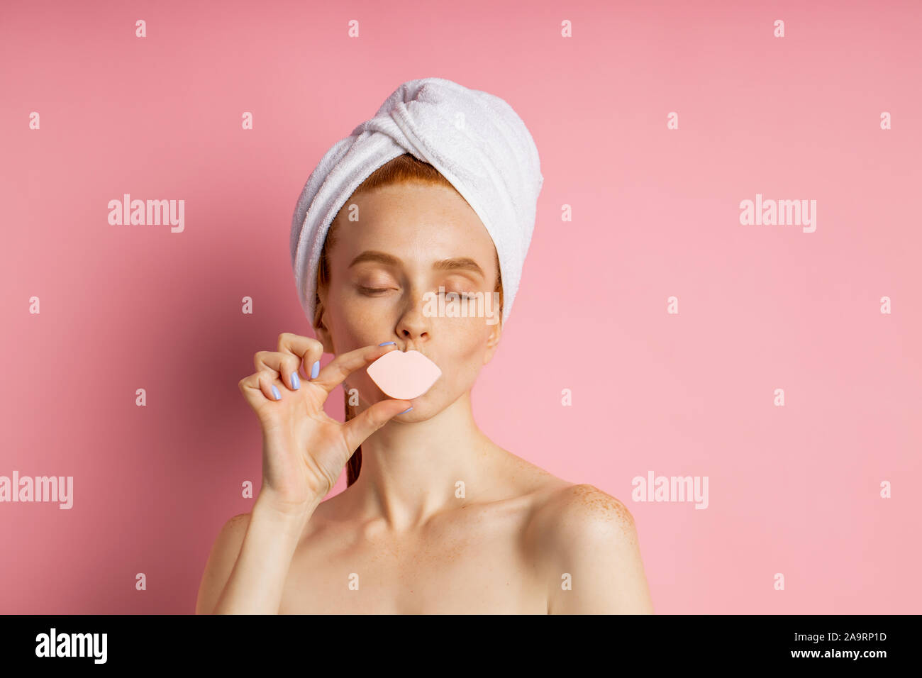 Studio shot of young woman with closed eyes, towel on head, fresh clean ...
