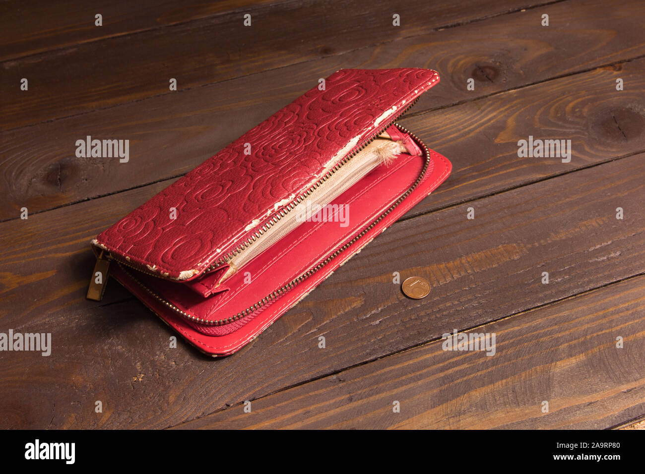 Old, worn out empty female red purse and 1 Euro cent on an empty wooden ...