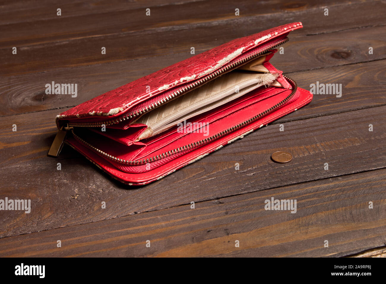 Old, worn out empty female red purse and 1 Euro cent on an empty wooden ...