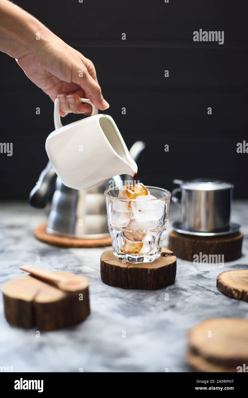 Vietnamese iced coffee. Slender woman hand pouring black coffee into ...