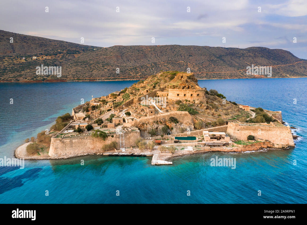 Aerial view of the island of Spinalonga with calm sea. Here were ...