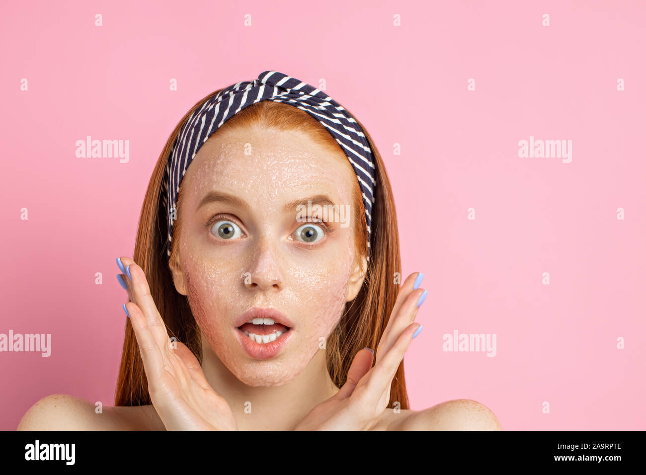 Surprised caucasian redhead woman with mask, peeling gel on face ...