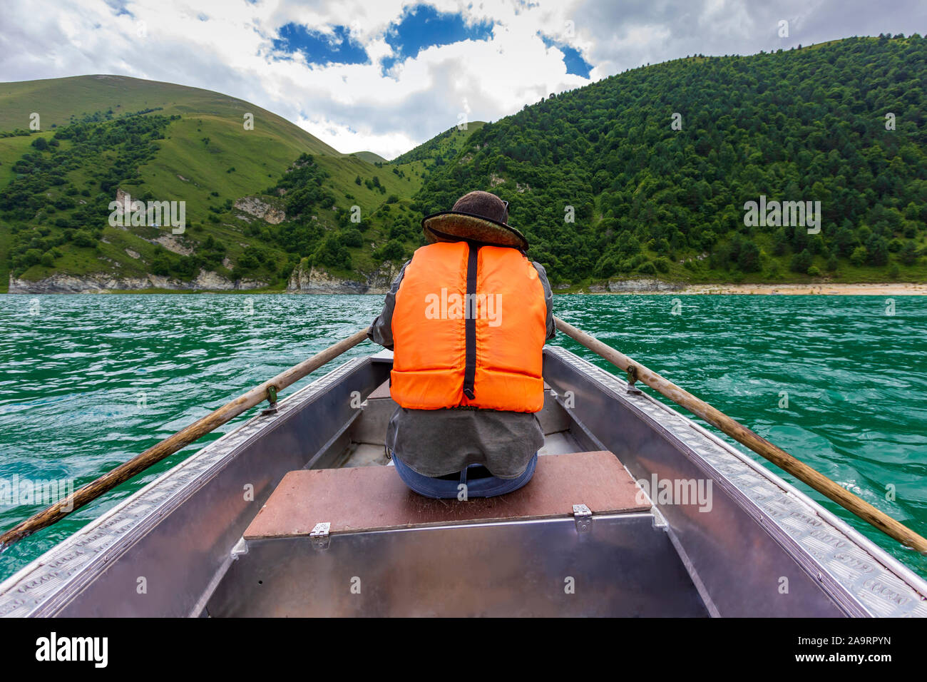 man rowing on a boat back view Beautiful mountain lake Kezenoy Am or ...