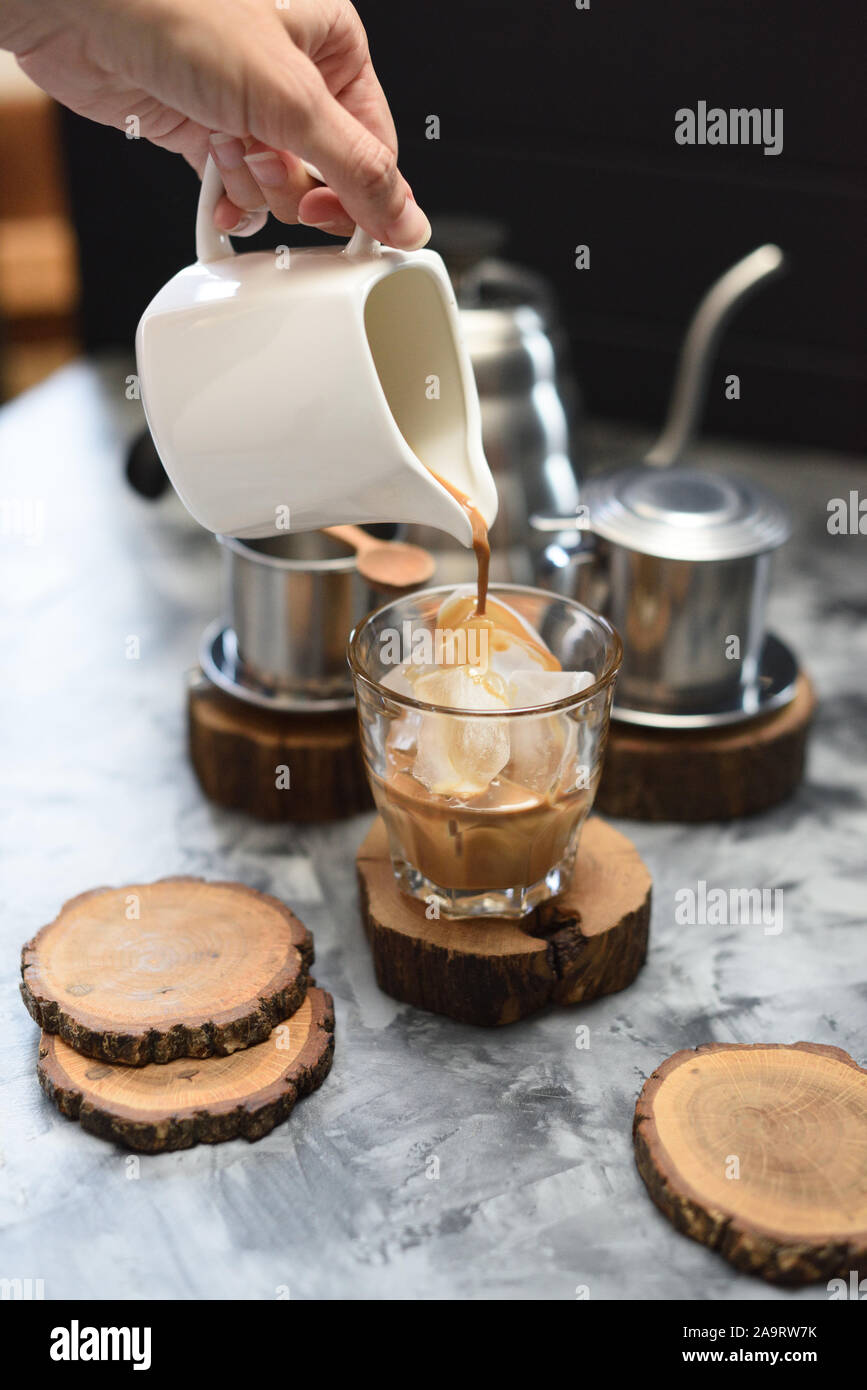 Making Vietnamese iced coffee. Slender woman hand pouring black coffee ...