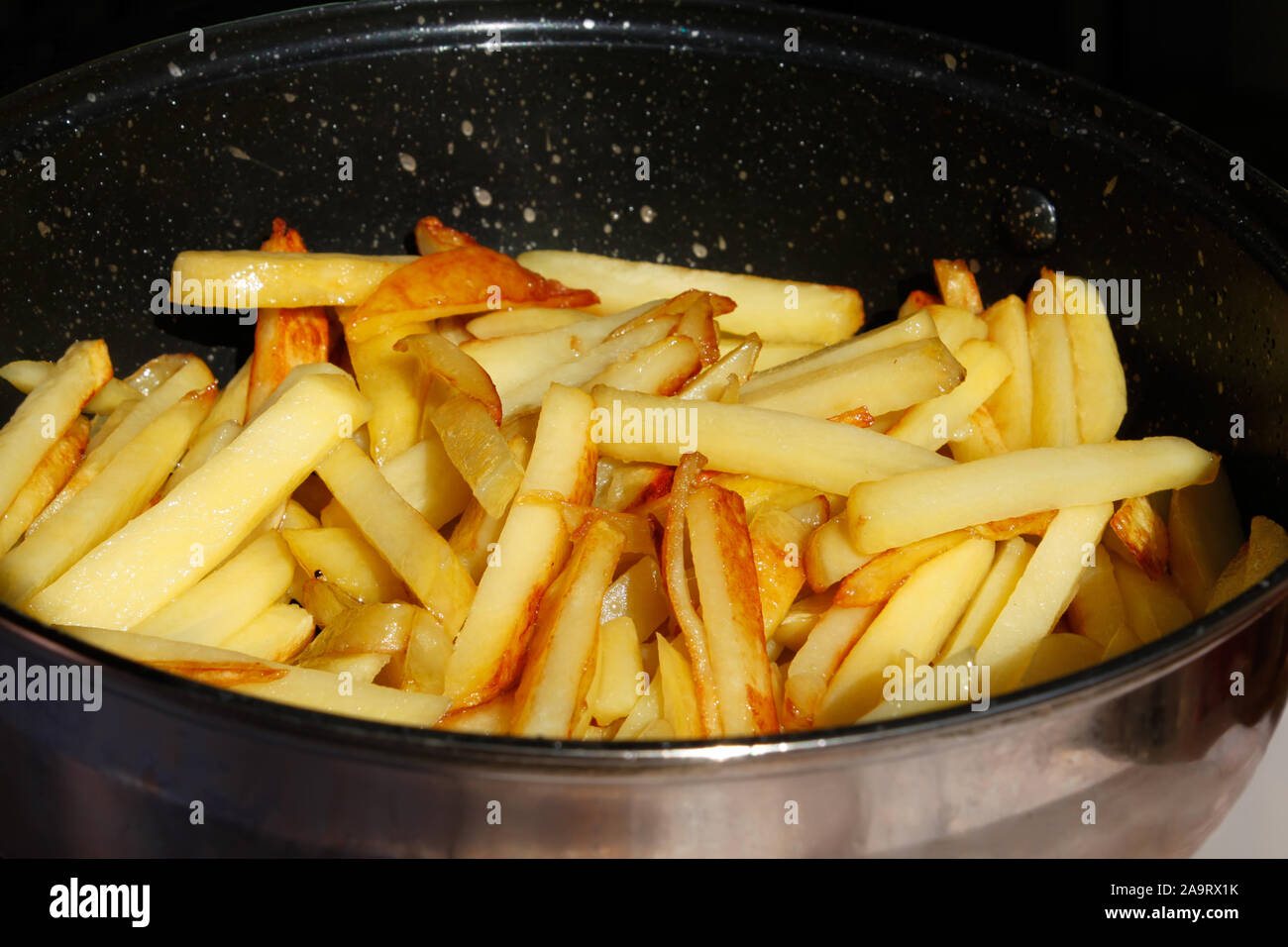 Roasted potato chips in a metal frying pan close-up, in bright sunlight ...