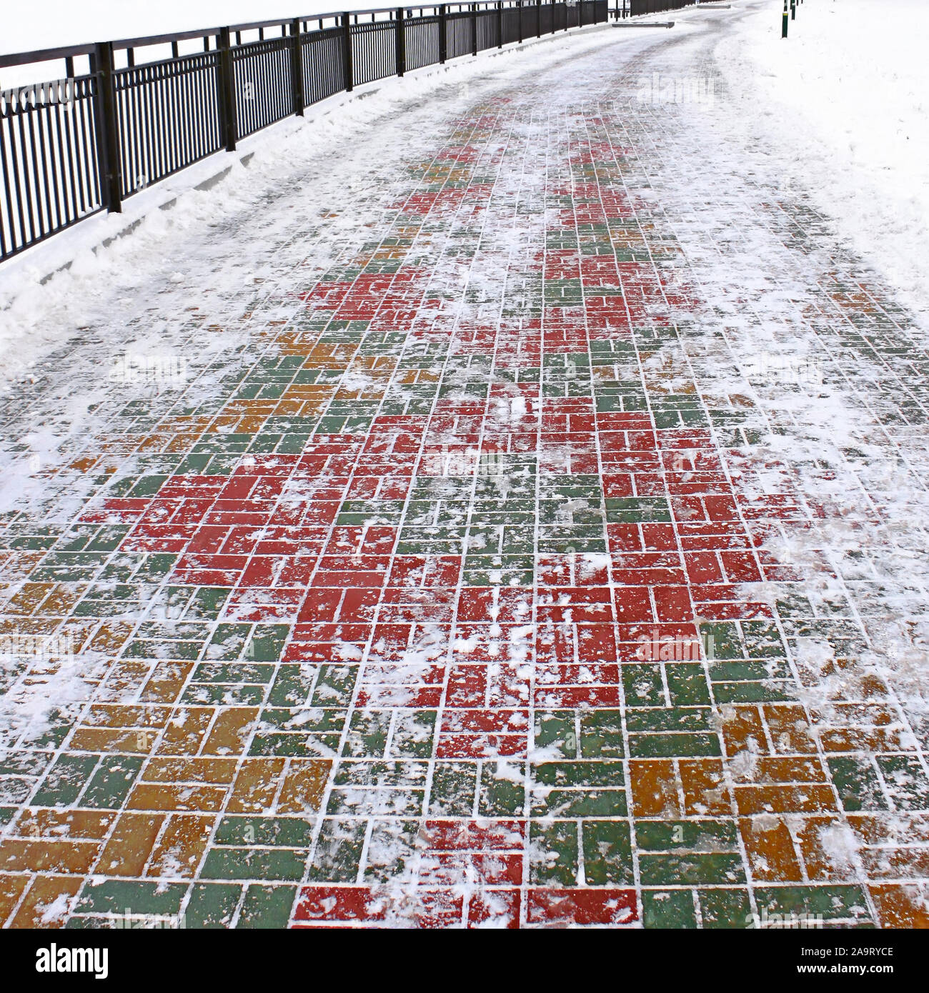 Sidewalk with colored tiles partially covered with snow in winter Stock ...
