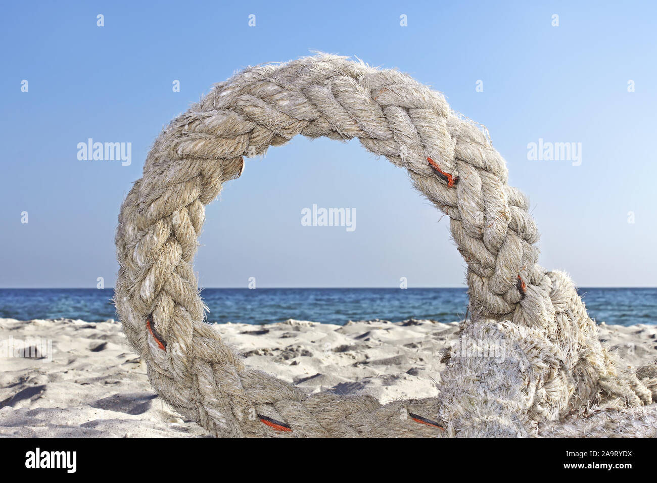 Old plaited artificial thick rope twisted into a ring lying on the ...