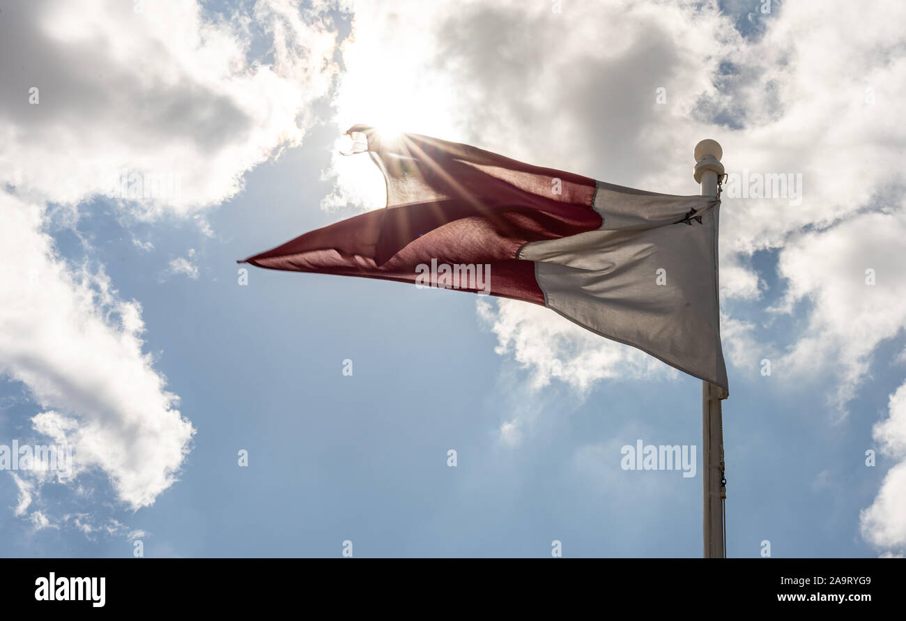 national flag of malta waving in the wind in front of the sun, valetta ...