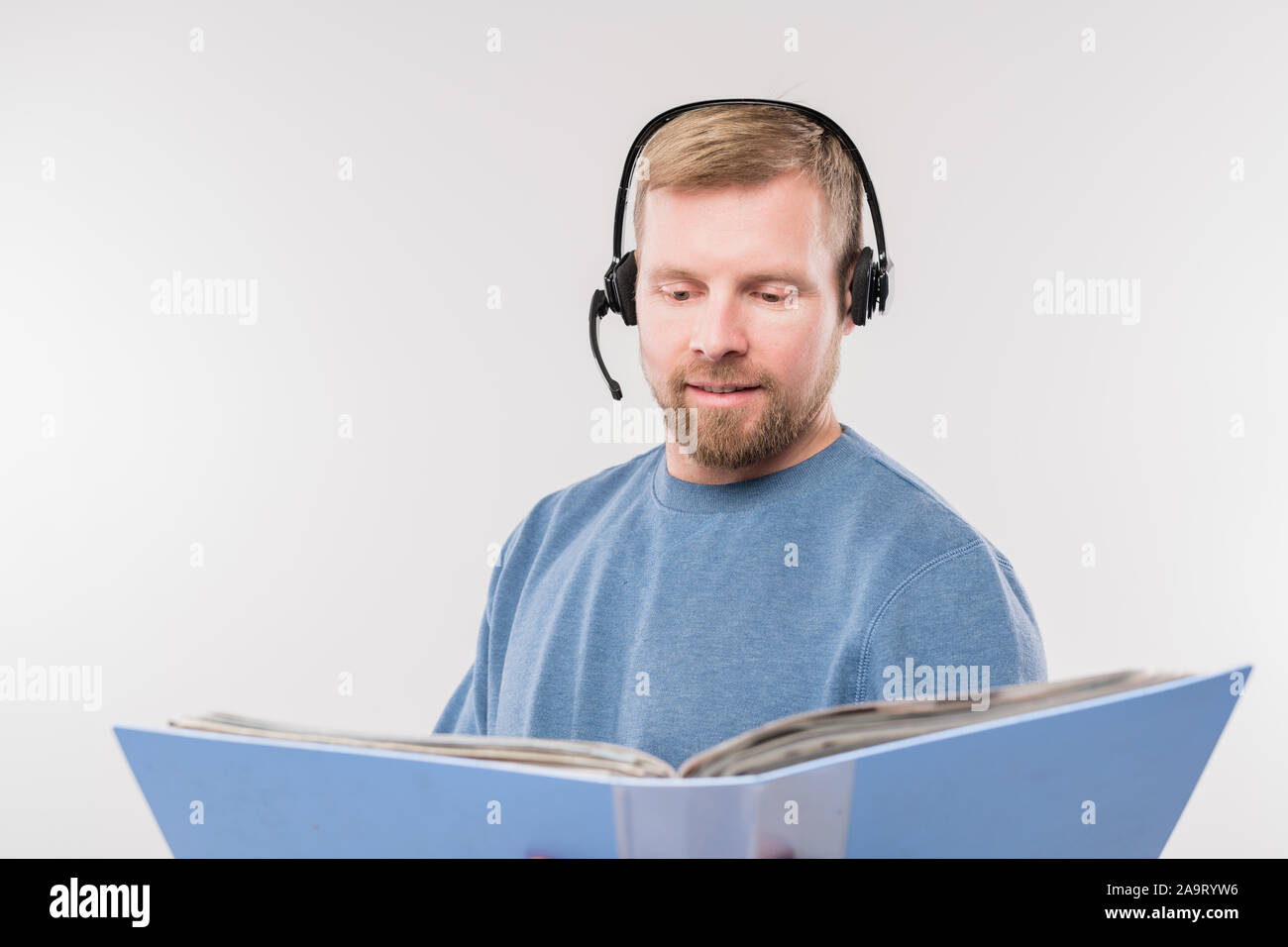 Bearded young operator with headset consulting clients while reading ...