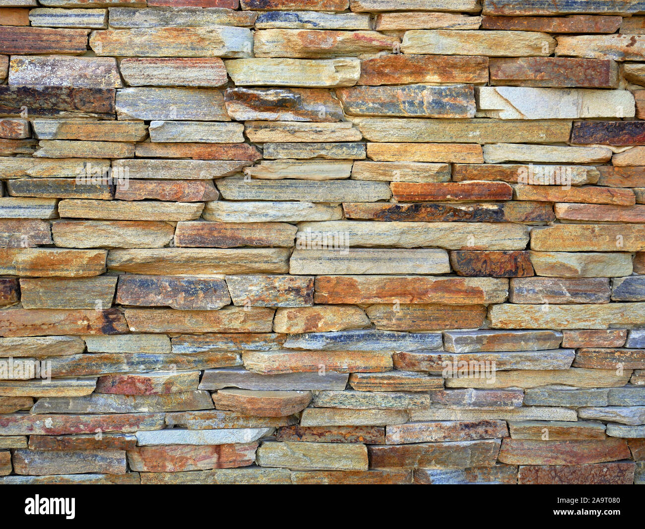 Color stone wall background in warm hues Stock Photo - Alamy