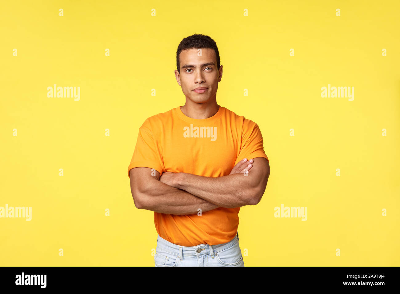 Self-assured motivated handsome man, bodybuilder in casual orange t ...