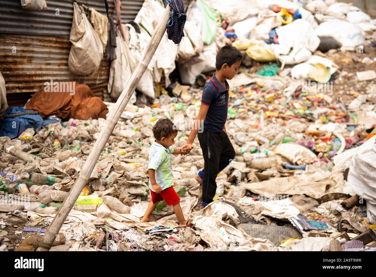 Two children walking among the garbage dump Stock Photo - Alamy