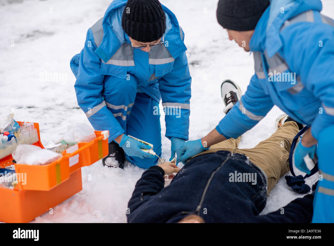 Two contemporary paramedics giving first aid to sick unconscious man ...