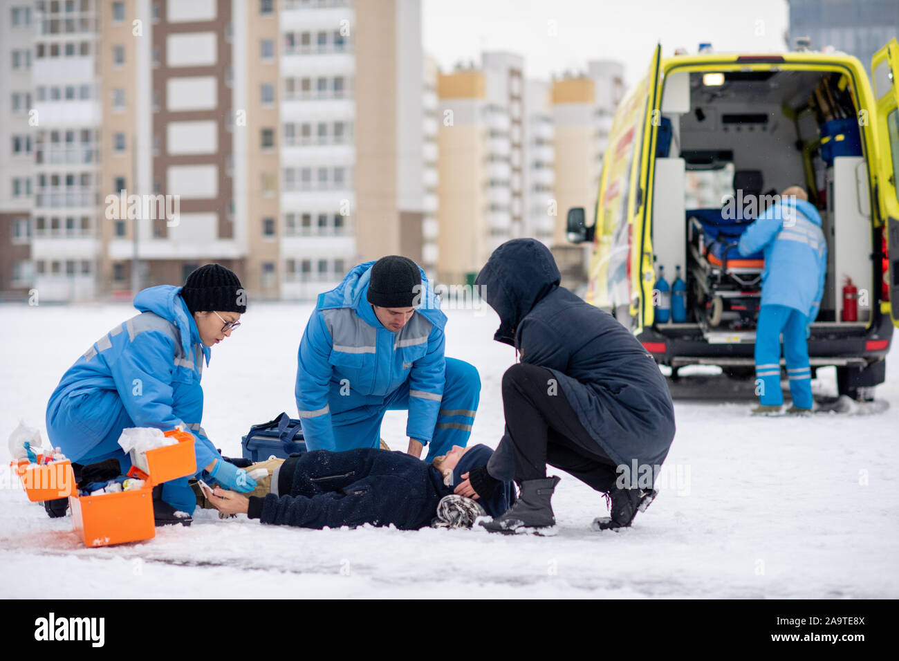 Two paramedics in uniform and guy giving first aid to sick unconscious ...