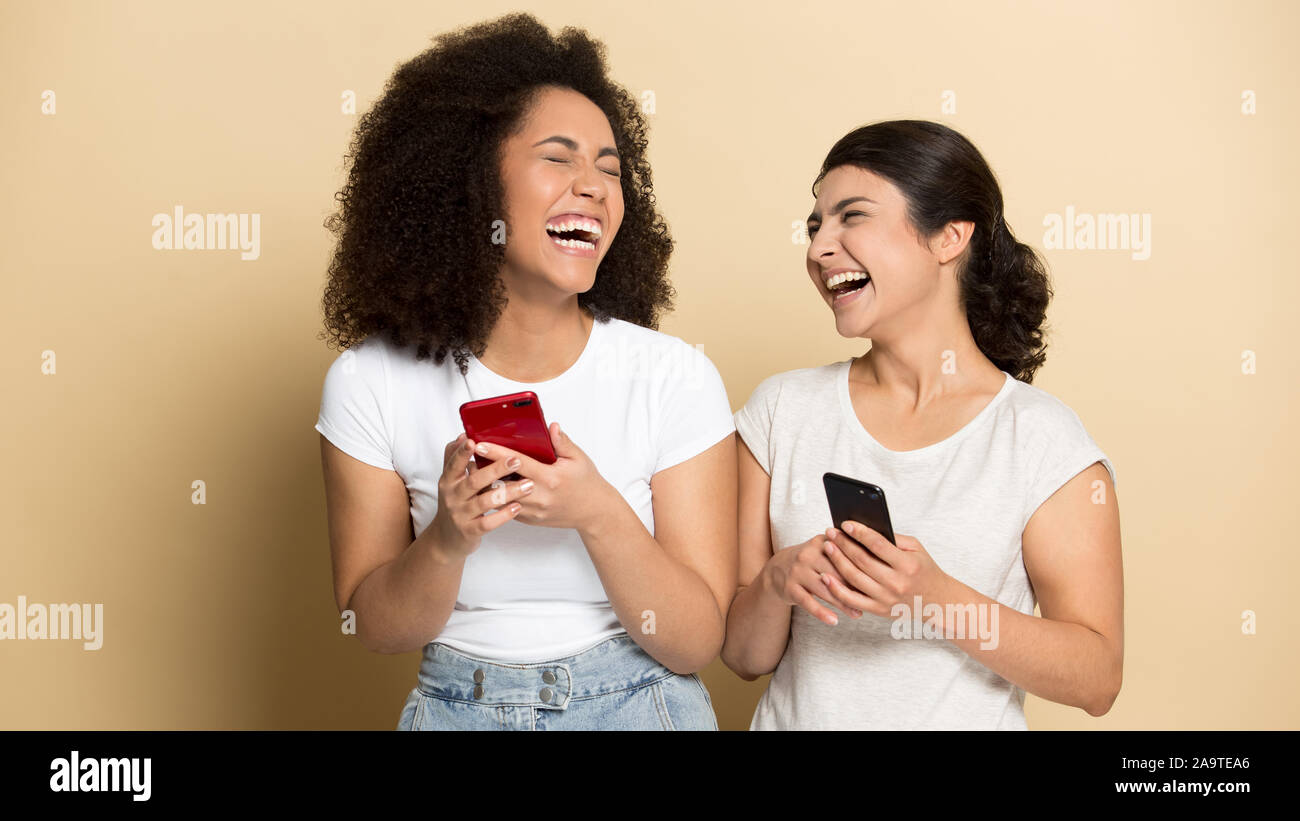Diverse beautiful girls using phones, laughing, having fun together ...