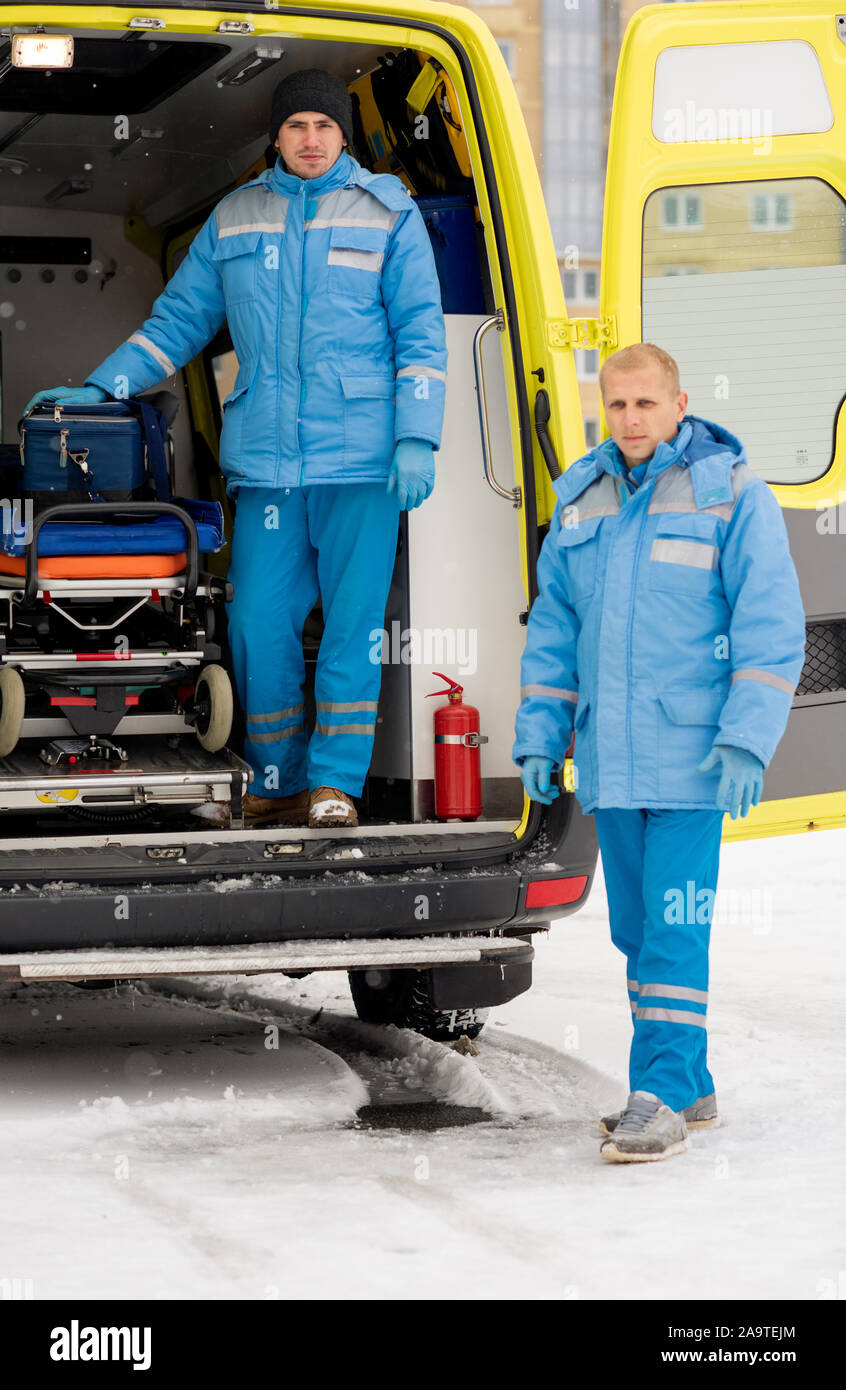 Two young male paramedics in workwear standing in front of camera ...