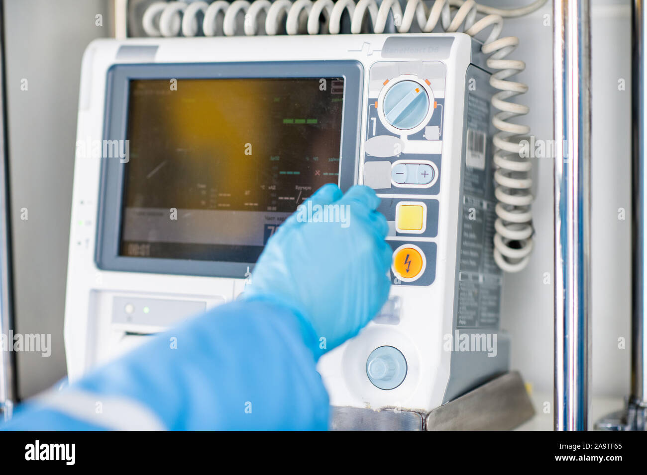 Gloved hand of paramedic going to press button on medical first aid ...