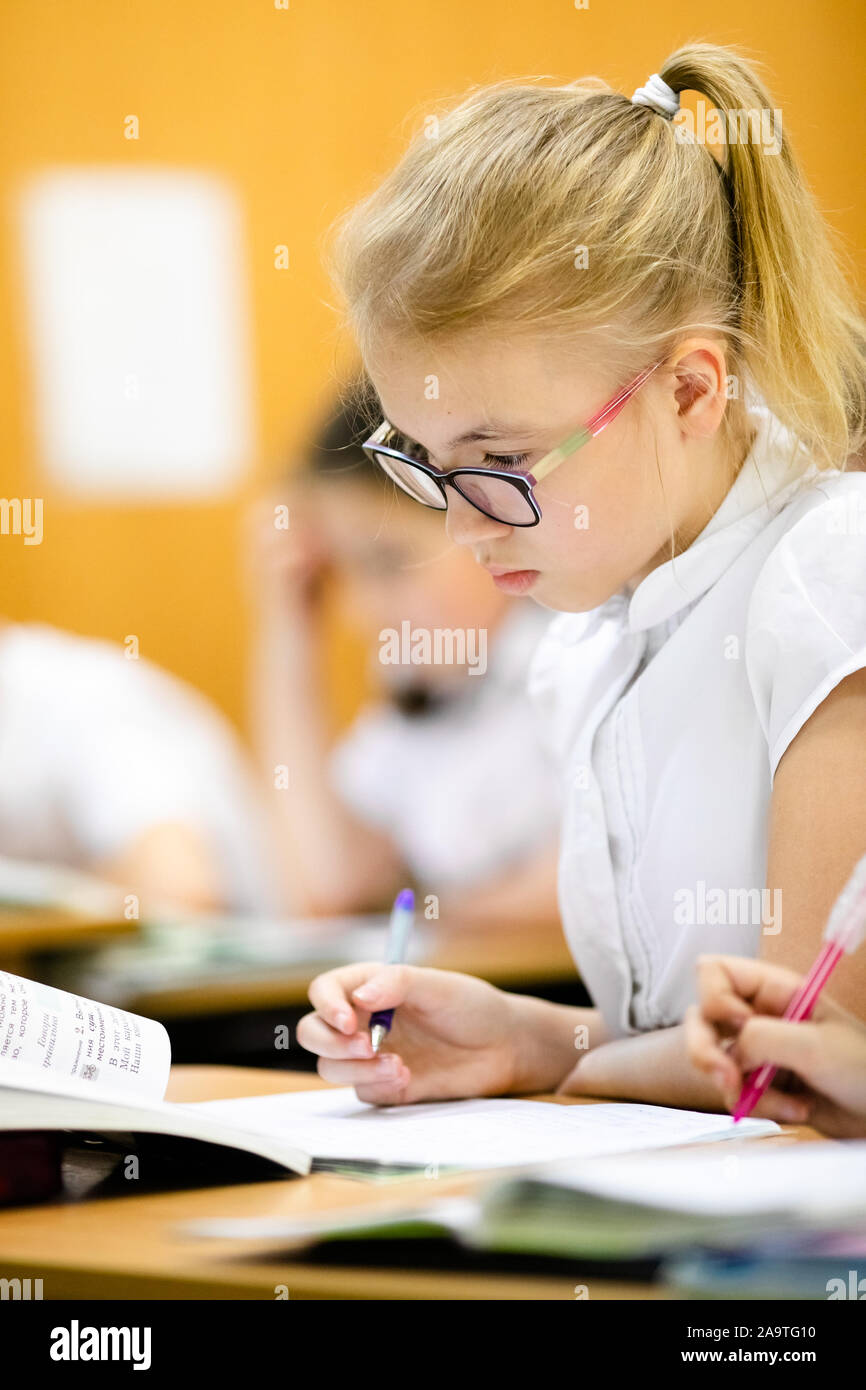 cute blonde school girl with stylish glasses writing in classroom Stock ...