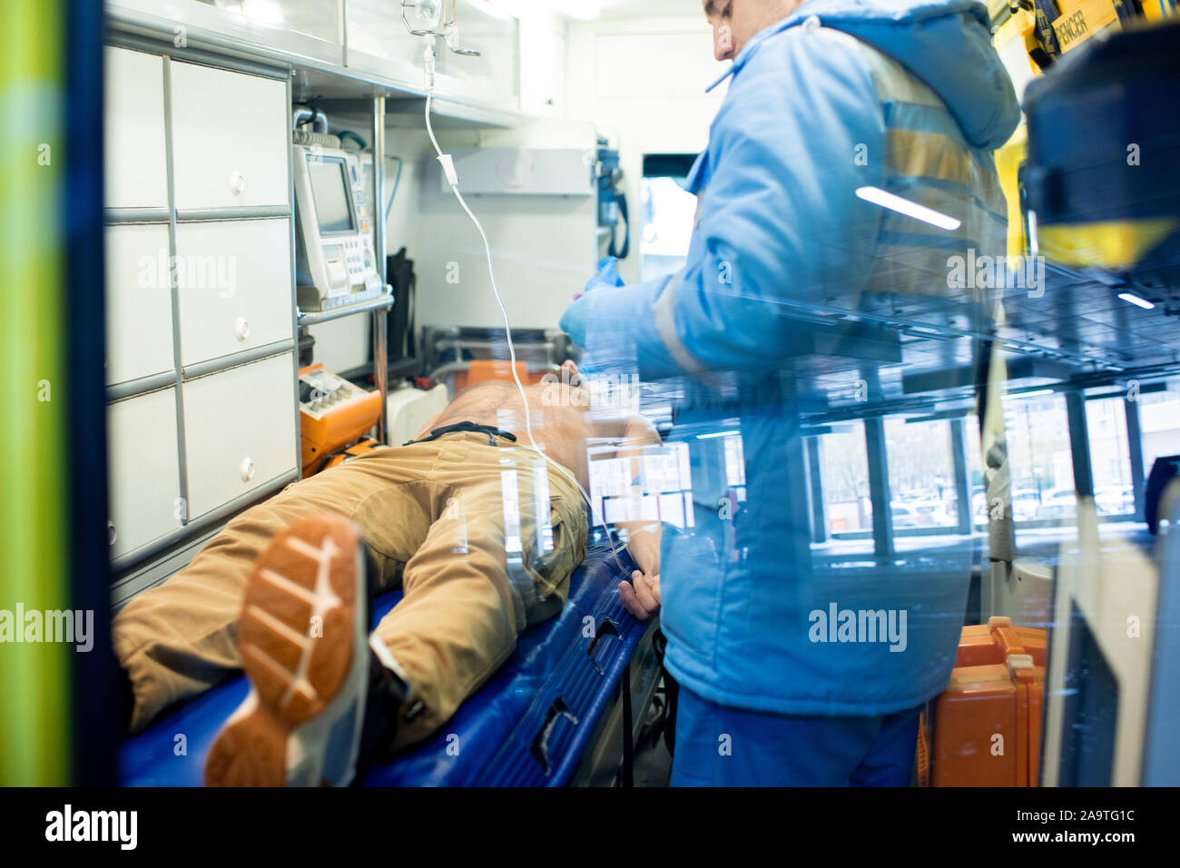Paramedic standing by stretcher with sick shirtless man and giving him ...