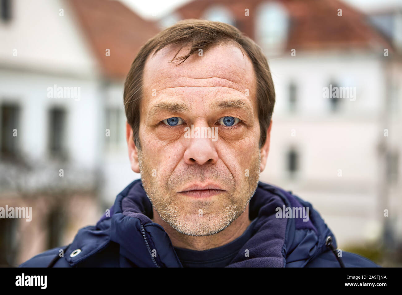 A serious face of a Caucasian middle-aged man, over 50, close-up, he is ...