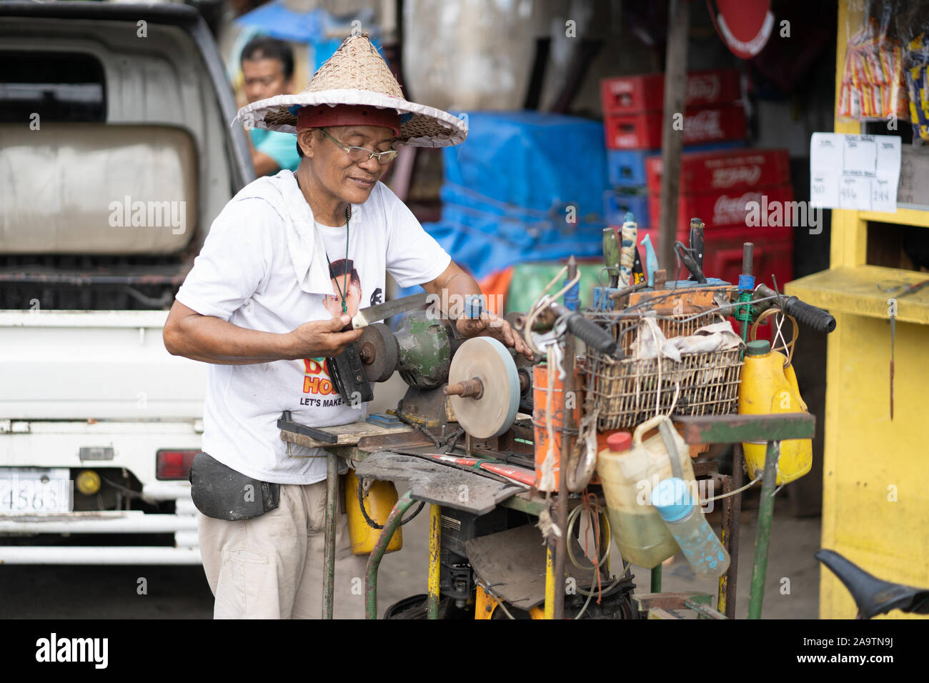A Filipino man using a grindstone to resharpen a knife,Cebu City ...