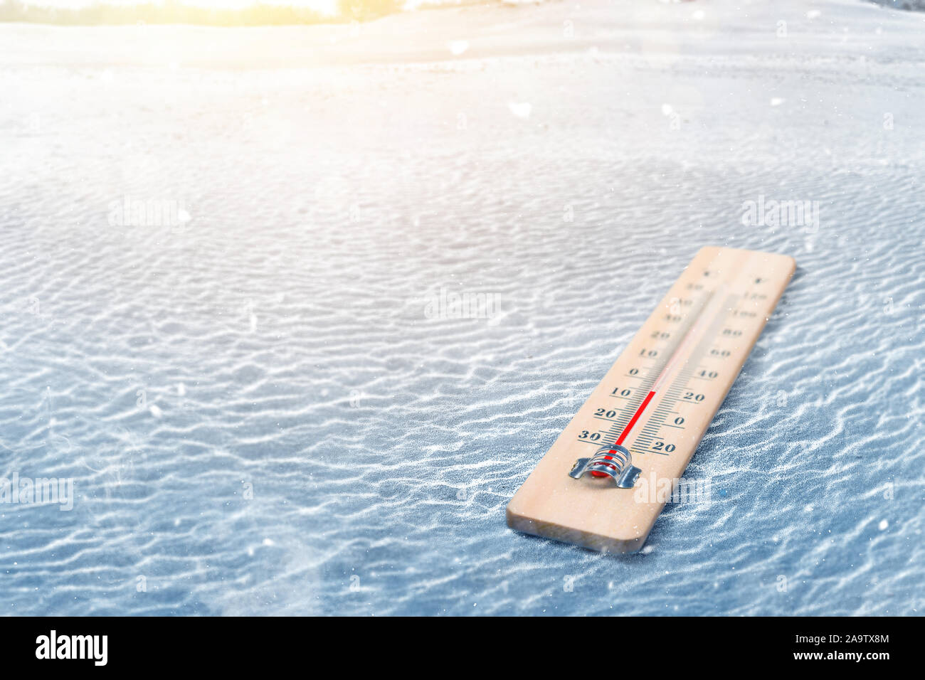 Wooden thermometer with the low temperature at winter with snowfall ...