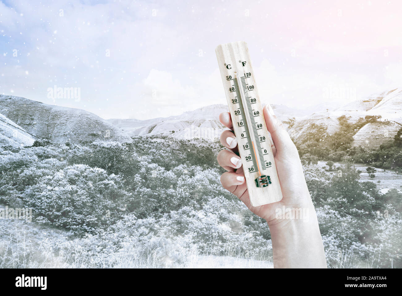 Hand holding thermometer measuring the temperature outdoor with a clear ...