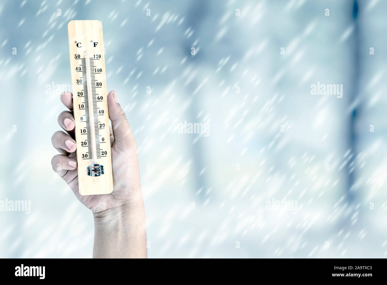 Hand holding wooden thermometer with the low temperature at winter with ...