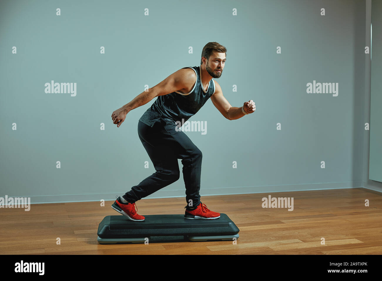 muscular young man training on step platforms on the gray background in ...