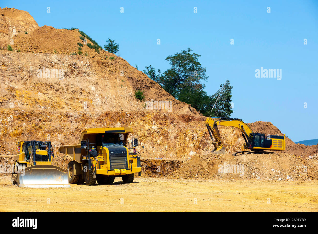 Gold mine dump trucks and excavator are seen in an opencast quarry ...