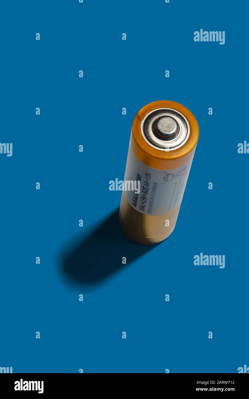 Alkaline AA orange metallic battery top view on blue background Stock ...