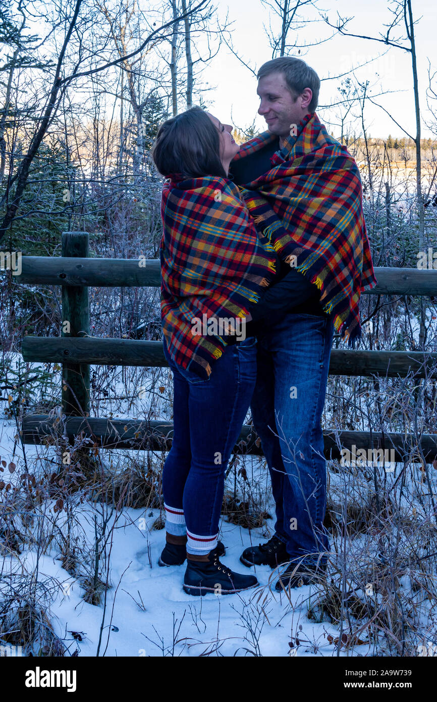 A beautiful young couple wrapped in a colorful blanket, in a hug, in a ...