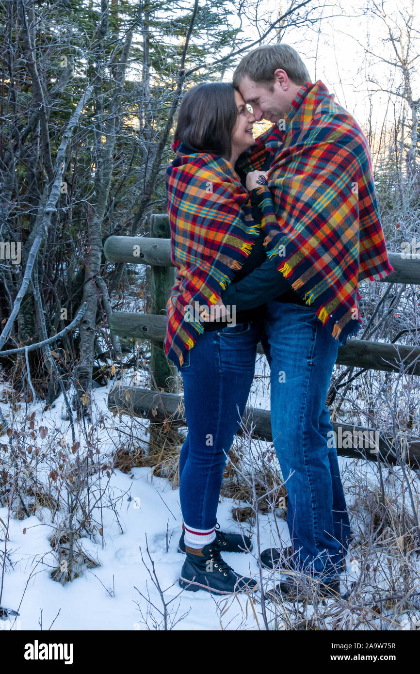 A beautiful young couple wrapped in a colorful blanket, in a hug, in a ...