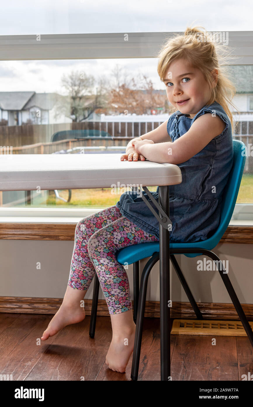 Very cute little girl sitting at a child size table Stock Photo - Alamy
