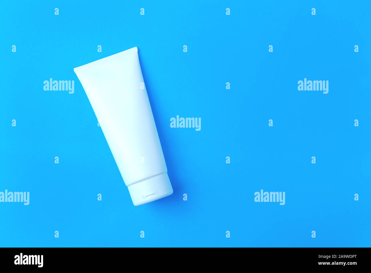 Blank white tube on blue background Stock Photo - Alamy