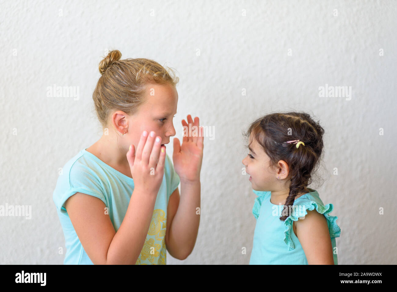Shocked teenager girl and her toddler girlfriends against white ...