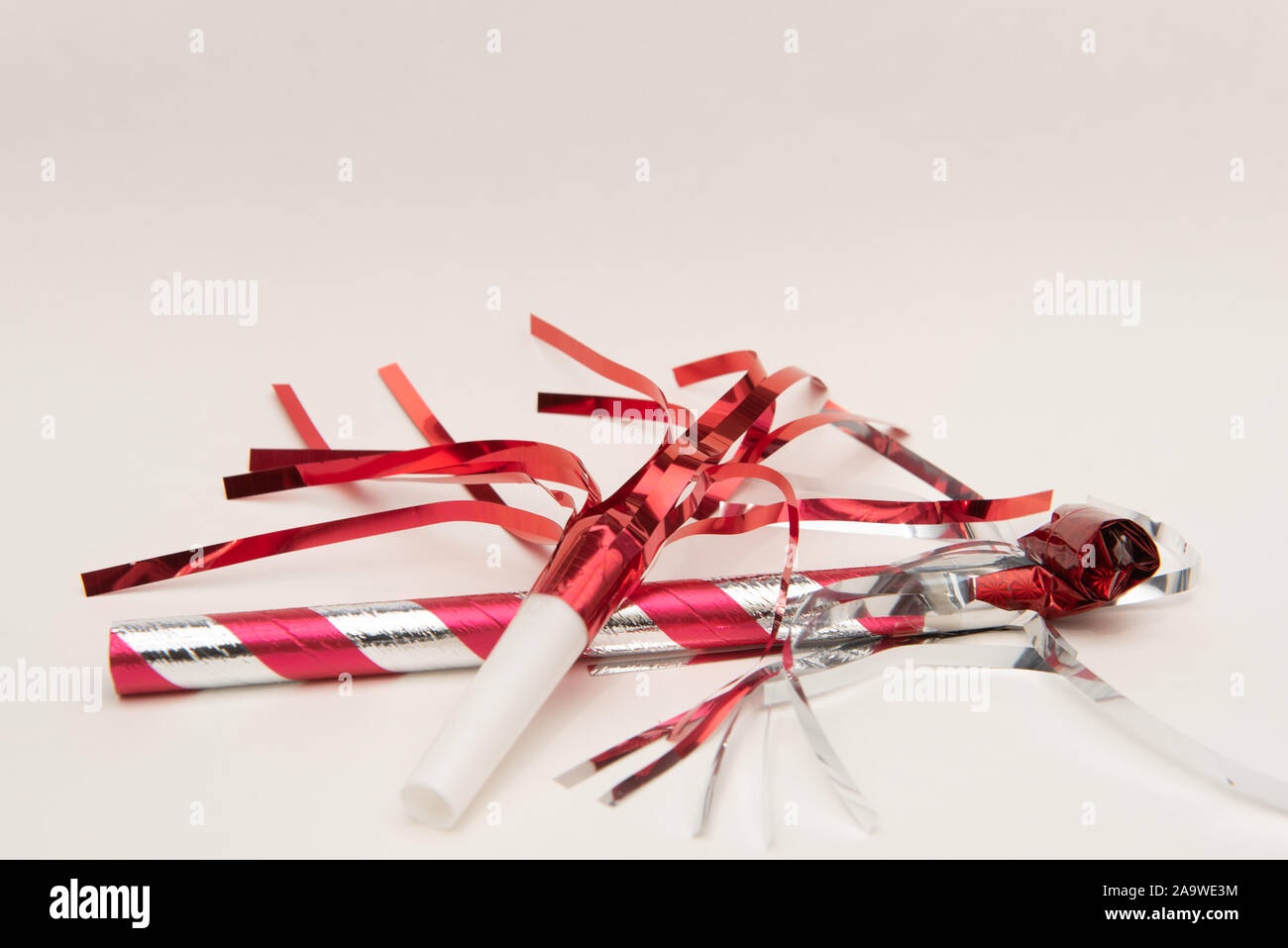 Isolated red party blowers on white background Stock Photo - Alamy
