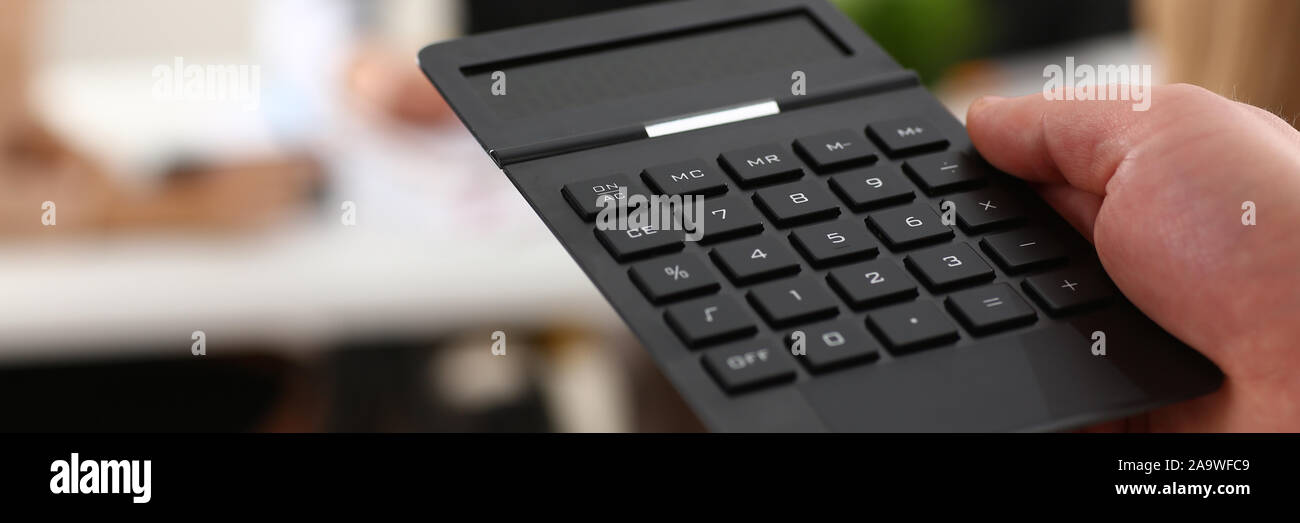 Male hand holding calculator at office Stock Photo - Alamy