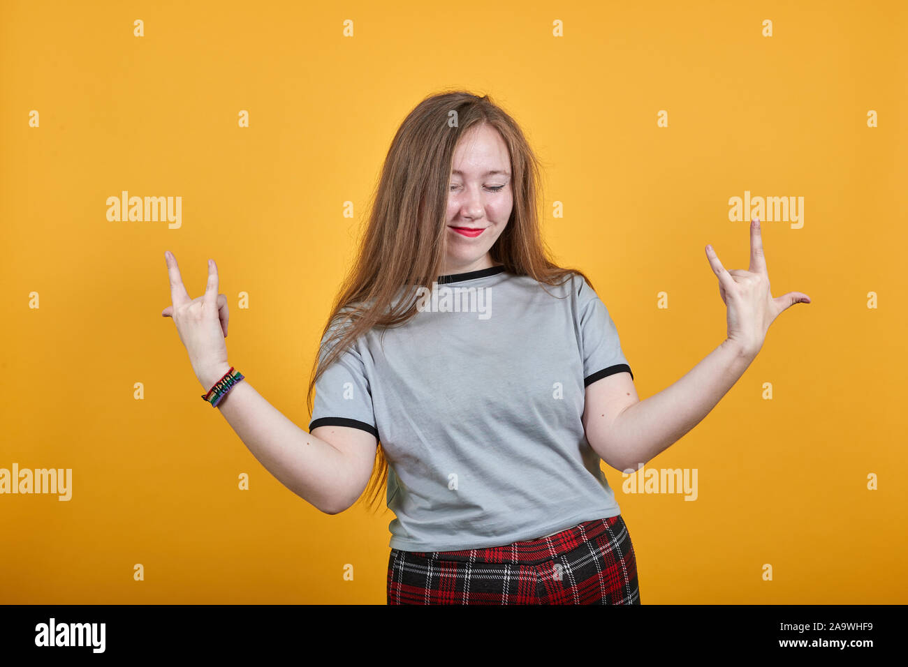Young woman smiling and laughing doing rock symbol Stock Photo - Alamy