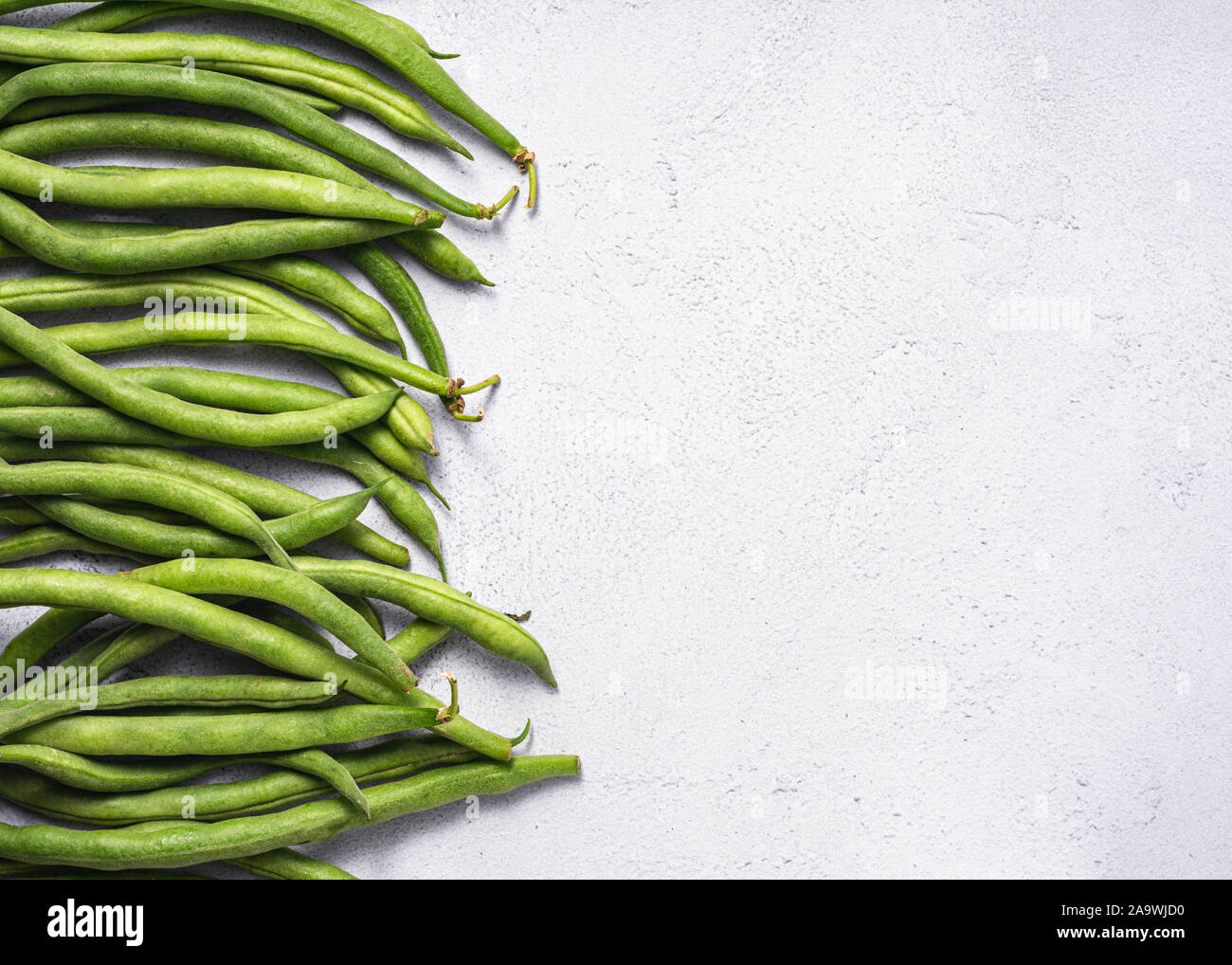 Fresh raw green beans left of frame on a textured white surface Stock ...
