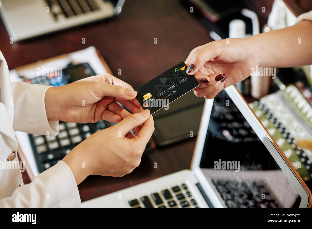 Hands of female client giving credit card to receptionist to pay for ...