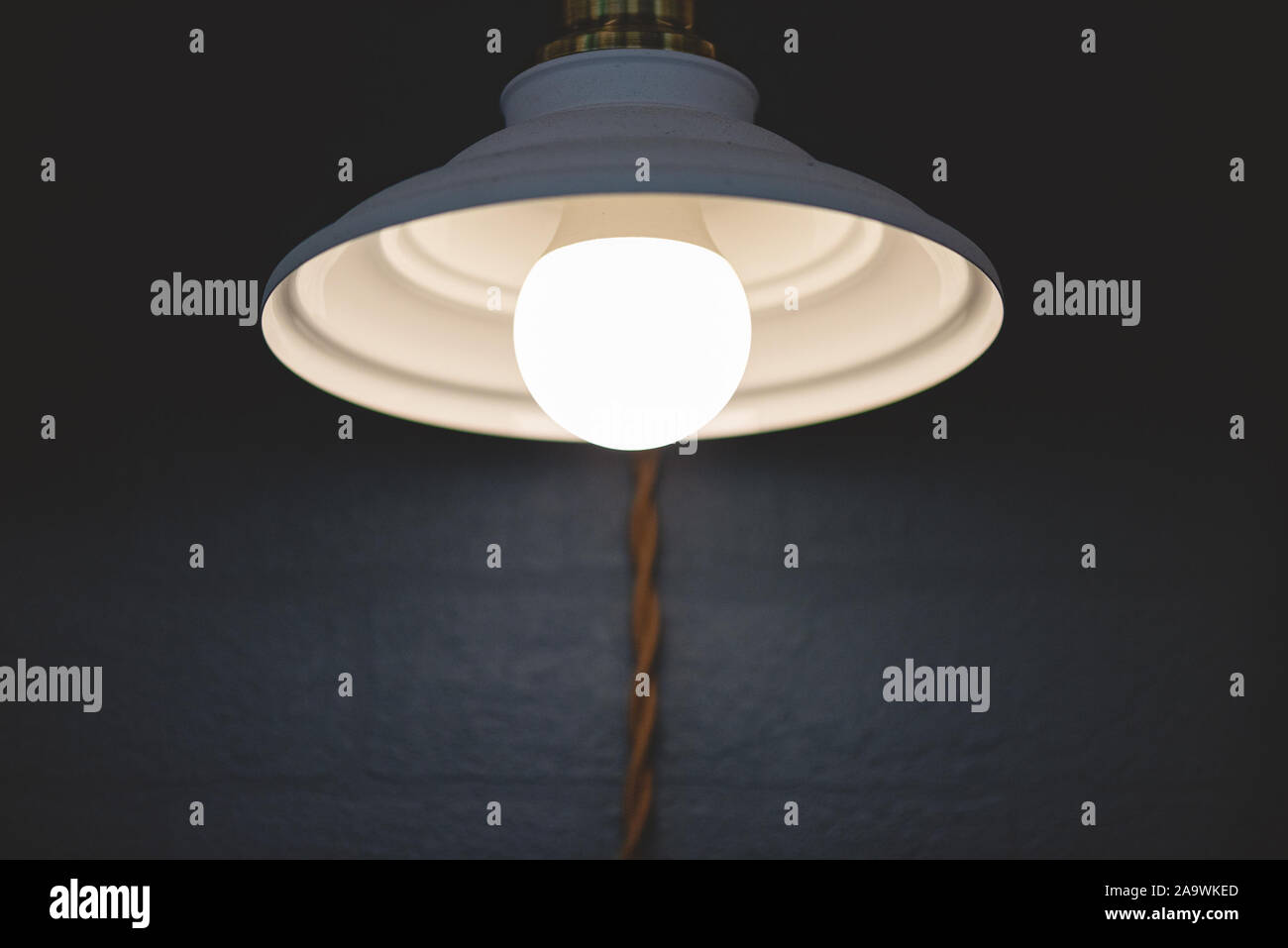 Turned on hanging lamp on a dark wall background Stock Photo - Alamy